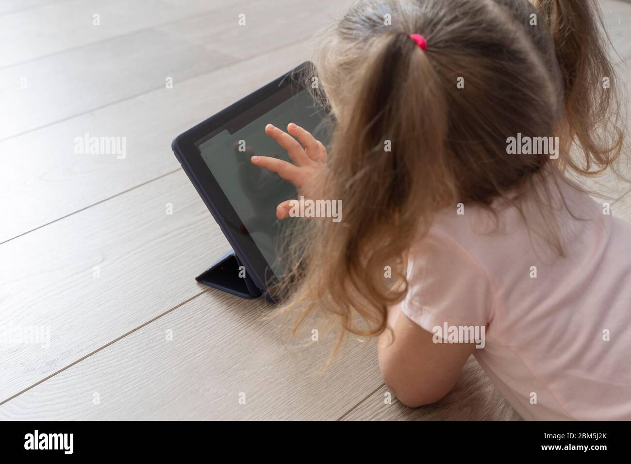 Little girl using a tablet pc. lying on the floor and swipes fingers on ...