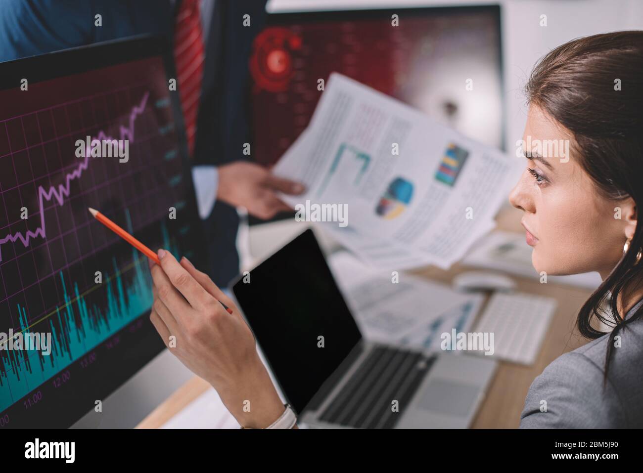 Selective focus of information security analyst pointing on charts on computer monitor near ...