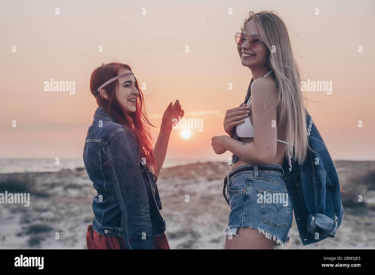 two young women go to the sea along the sandy shore back view slow ...