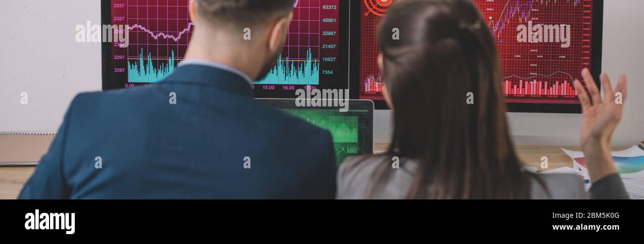Back view of data analysts working on strategy of security with graphs on computer monitors ...
