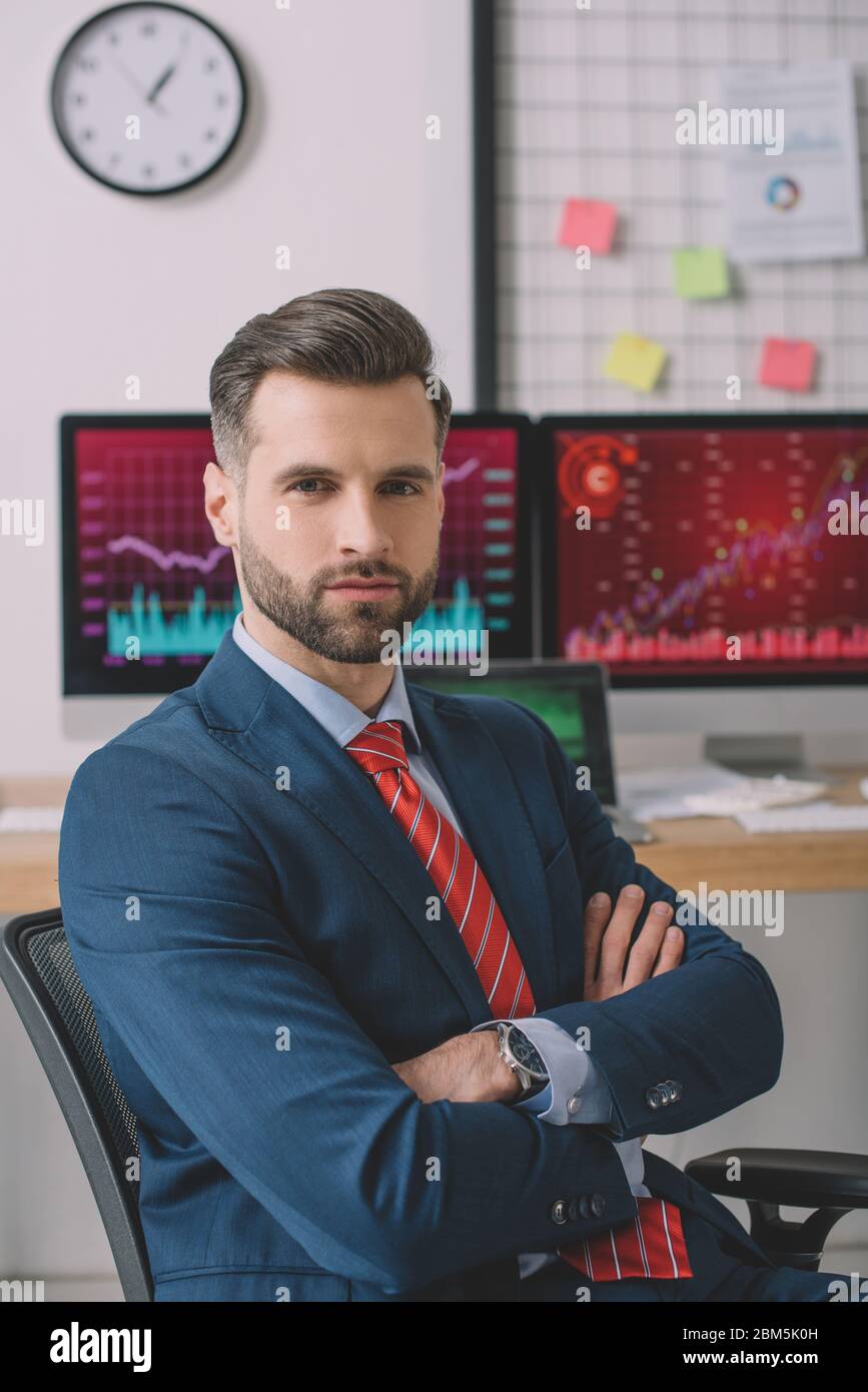 Handsome data analyst with crossed arms looking at camera in office ...