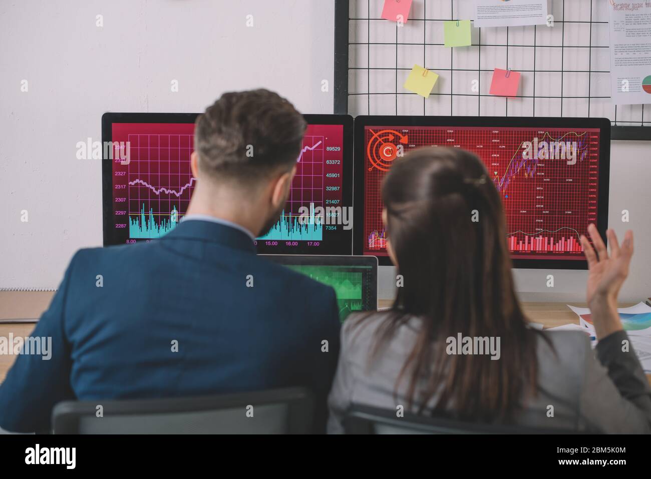 Back view of data analysts working on strategy of security with graphs on computer monitors ...