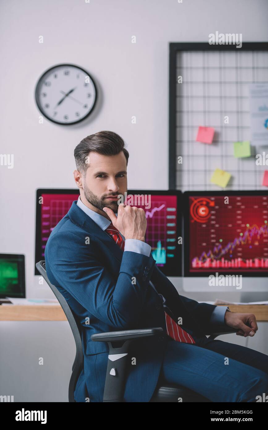 Handsome data analyst looking at camera near charts on computer ...