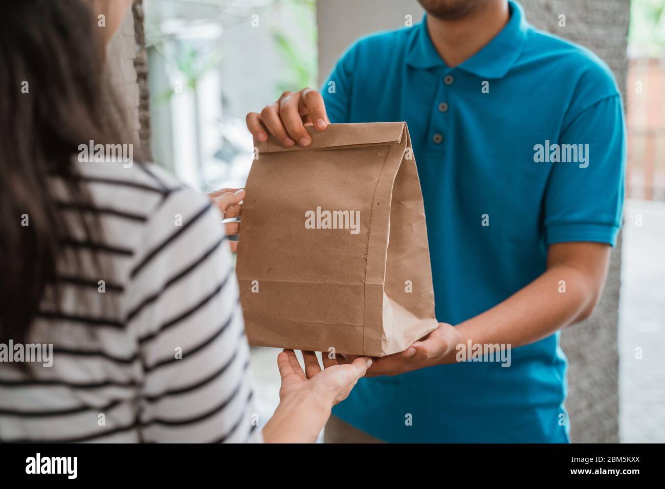 Delivery man delivering food to a woman at home. online food shopping ...