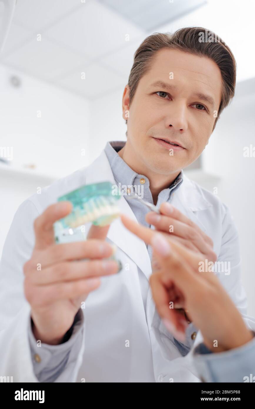 selective focus of dentist looking at patient pointing with finger at ...