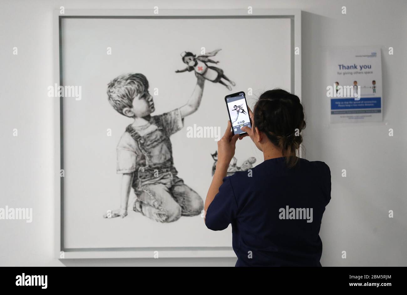 A member of staff takes a photograph of the new artwork painted by ...