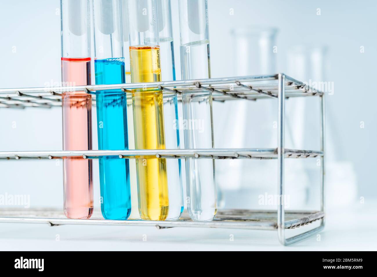 Close up of lab test tubes fill with red, blue, yellow and clear liquid ...
