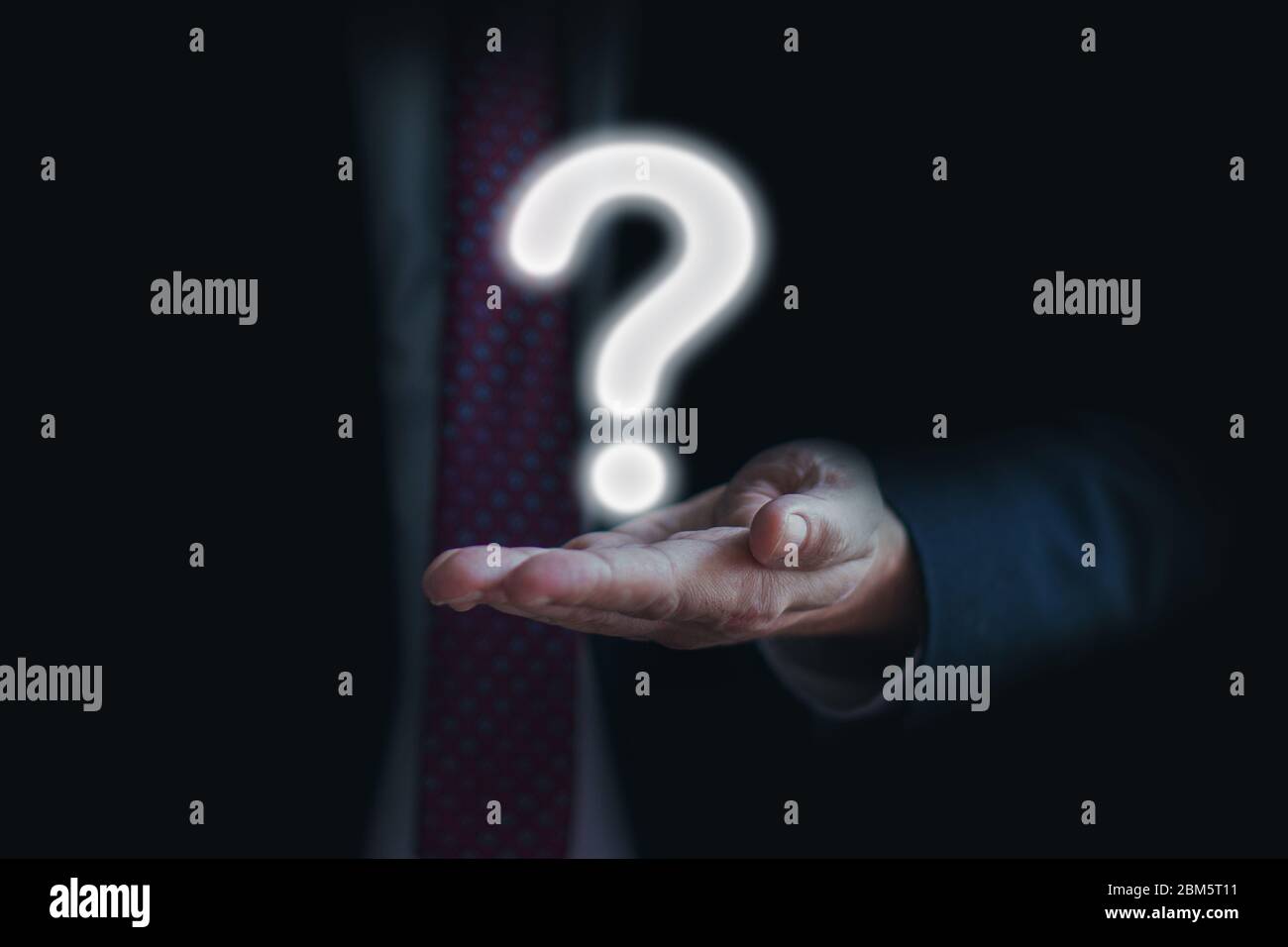 Businessman on blurred background question mark with his palm. Asking ...
