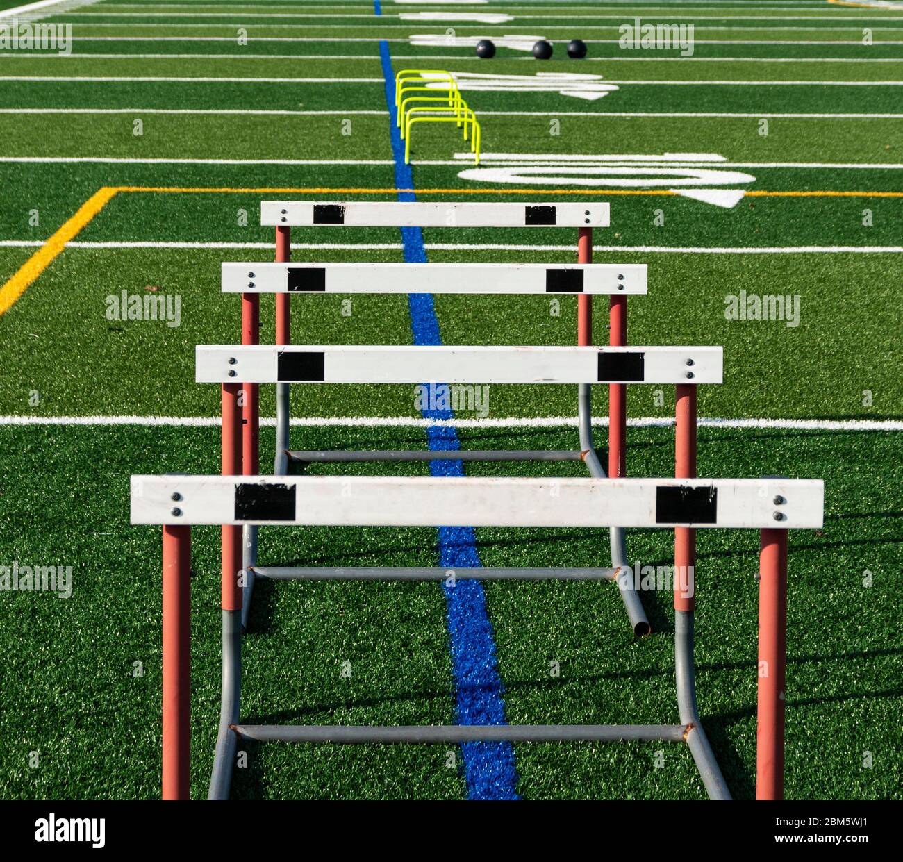 Mini and regular hurdles are set up on a green turf field for speed and agility practice Stock ...