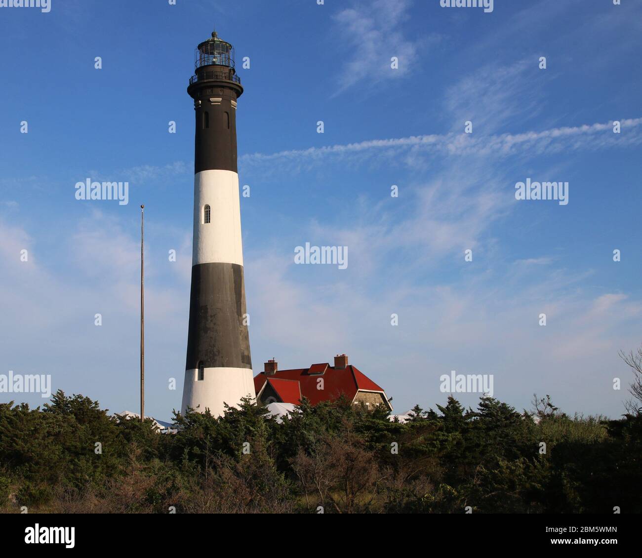 Fire Island Lighthouse with a deep blue sky and some light clouds ...