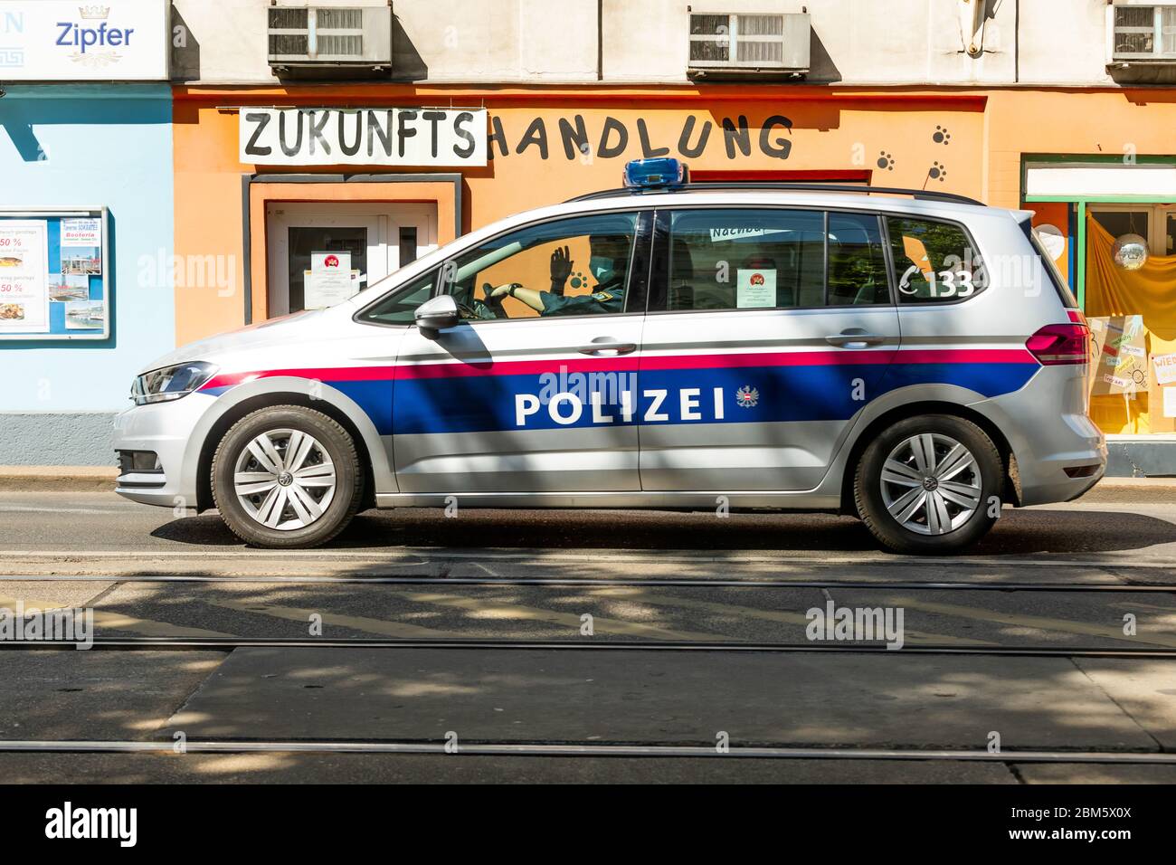 police car is driving along a storefront with a banner ribbon saying ...