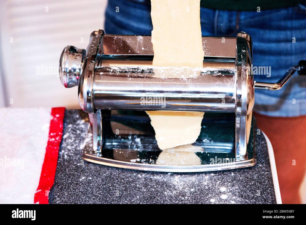 Fresh pasta being rolled through a past making machine Stock Photo - Alamy