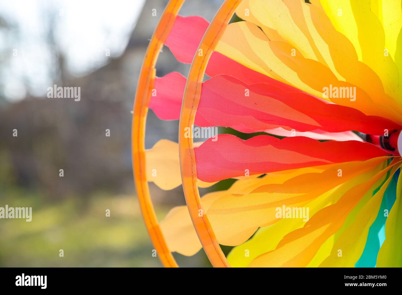 Colorful pinwheel spinning in the wind in front of a natural green ...