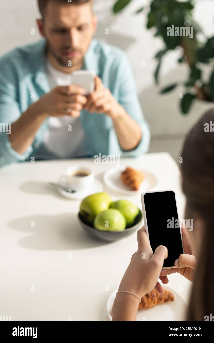 Selective focus of woman using smartphone with blank screen during ...
