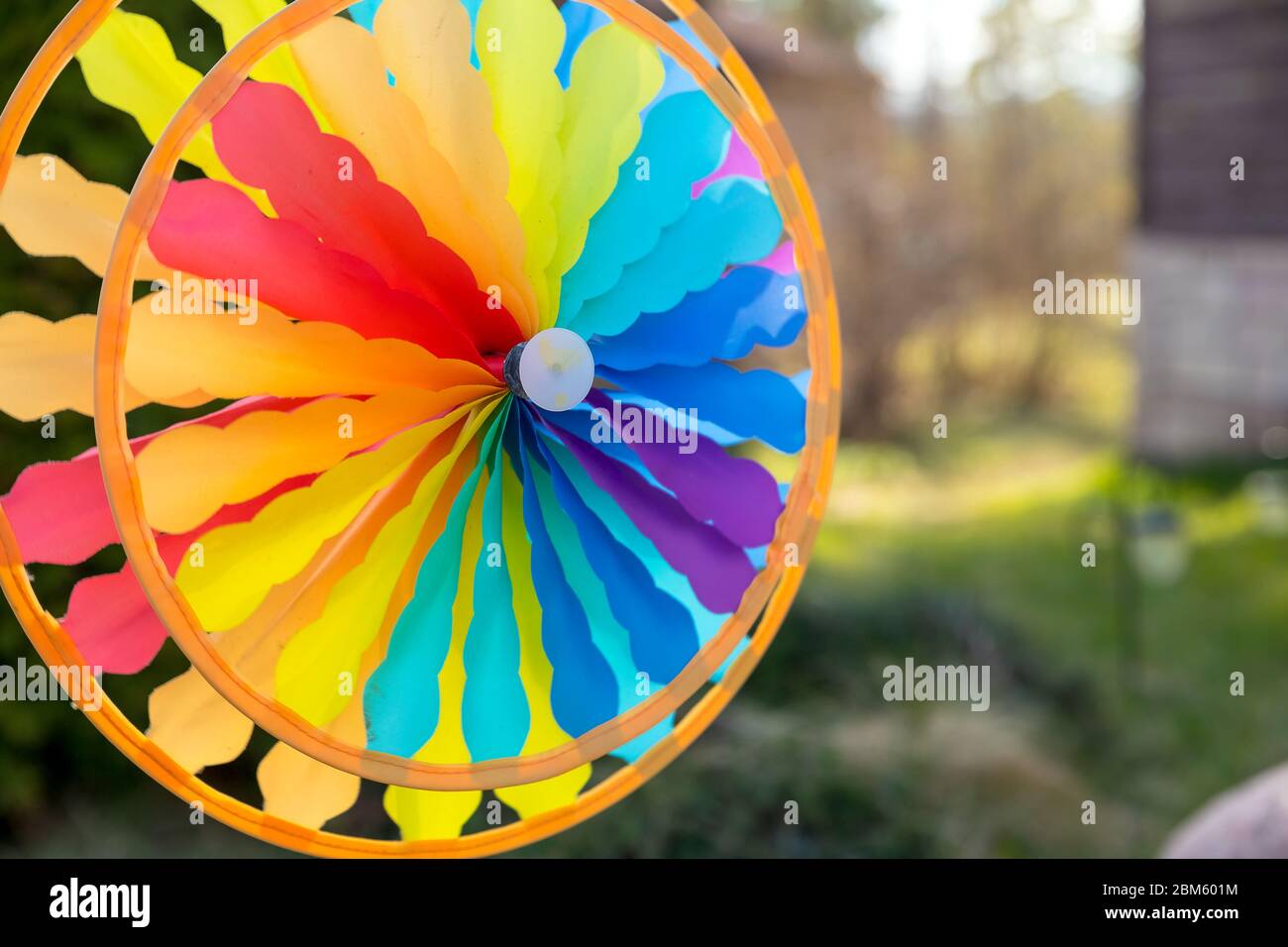 Colorful pinwheel spinning in the wind in front of a natural green ...