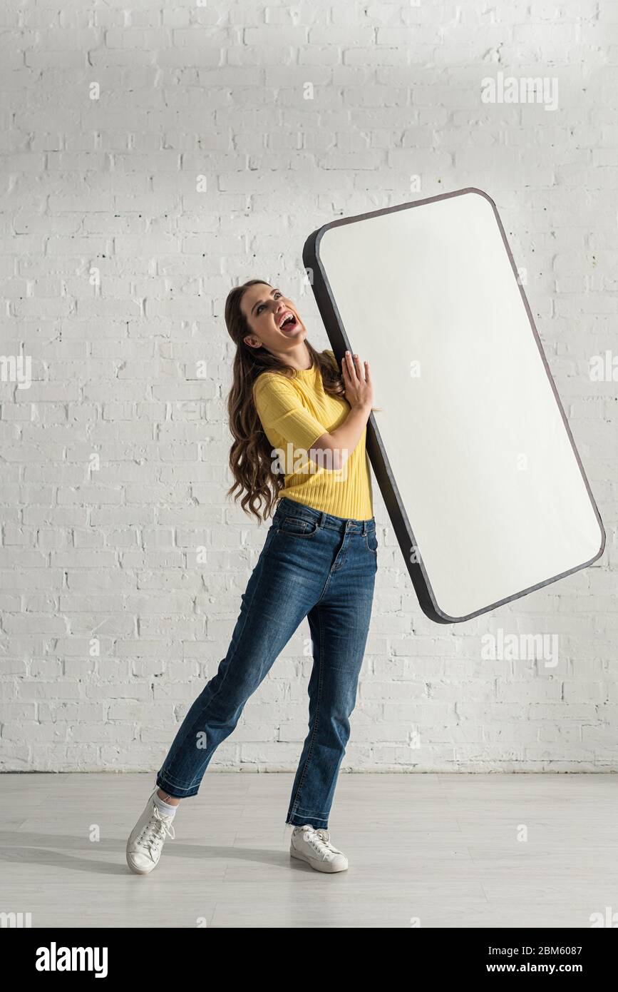 Beautiful laughing woman holding model of smartphone at home Stock ...