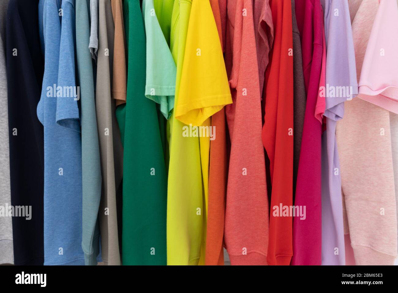 Rainbow colors clothes on hangers for background Stock Photo - Alamy