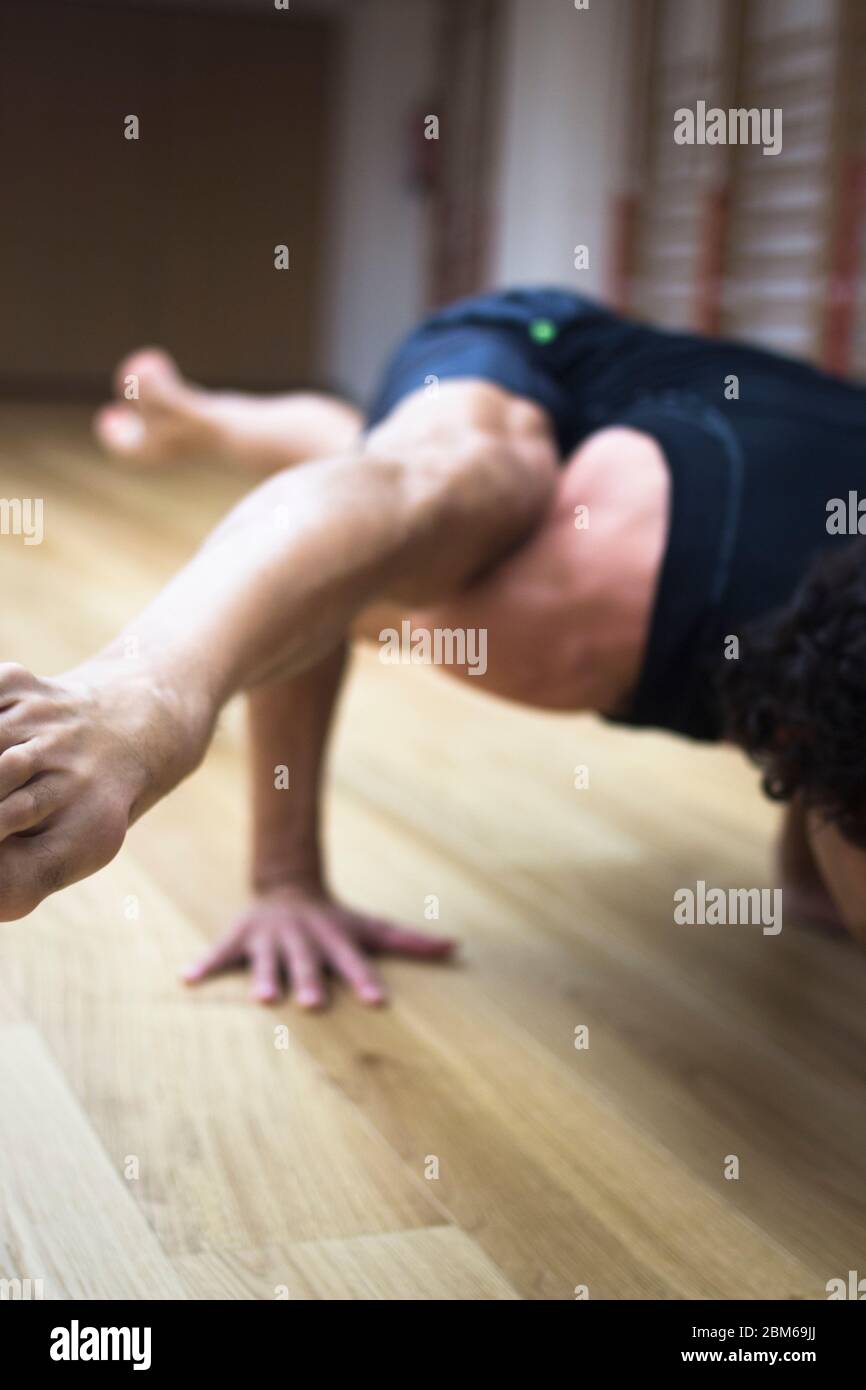 Man yoga teacher practising in gym fitness studio doing advanced asana ...
