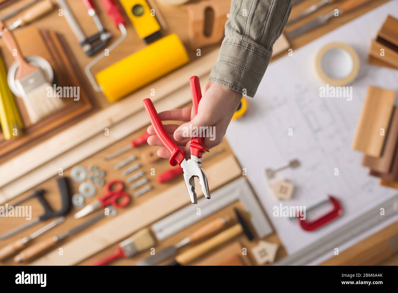 Male hand holding pliers, work table with construction and repair tools ...