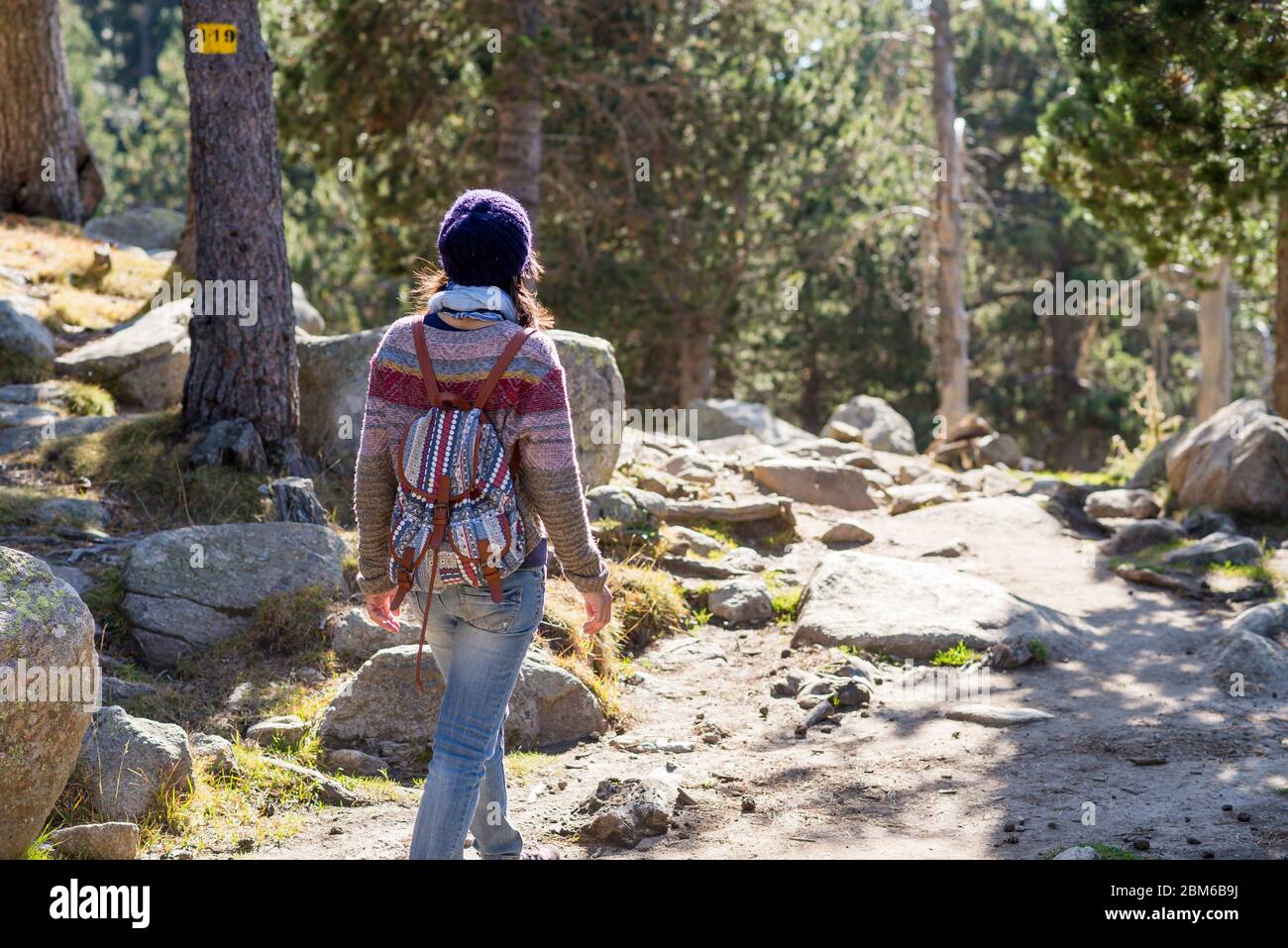 Back view of a backpacker woman wearing a wool cap hiking Stock Photo ...