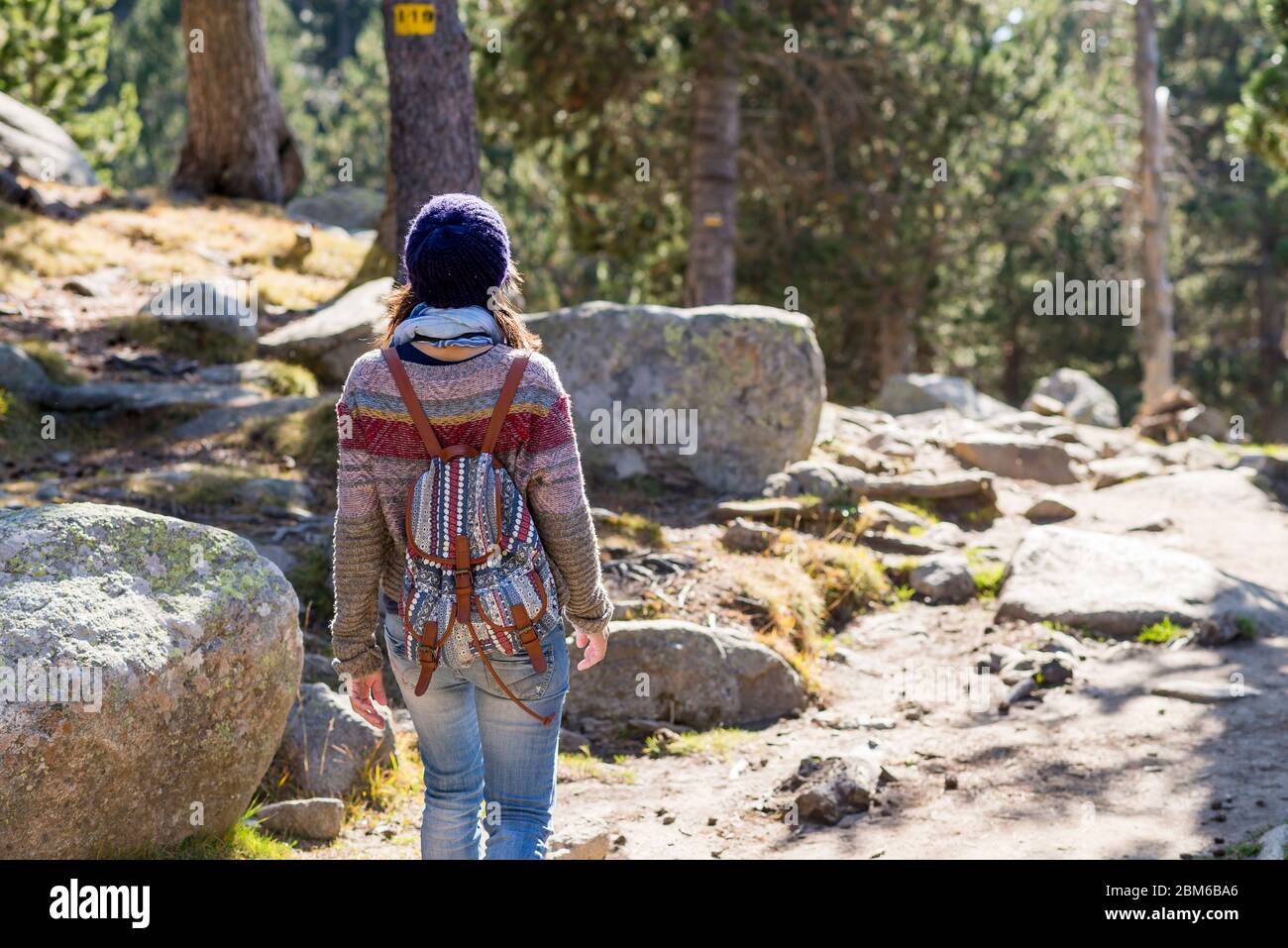 Back view of a backpacker woman wearing a wool cap hiking Stock Photo ...