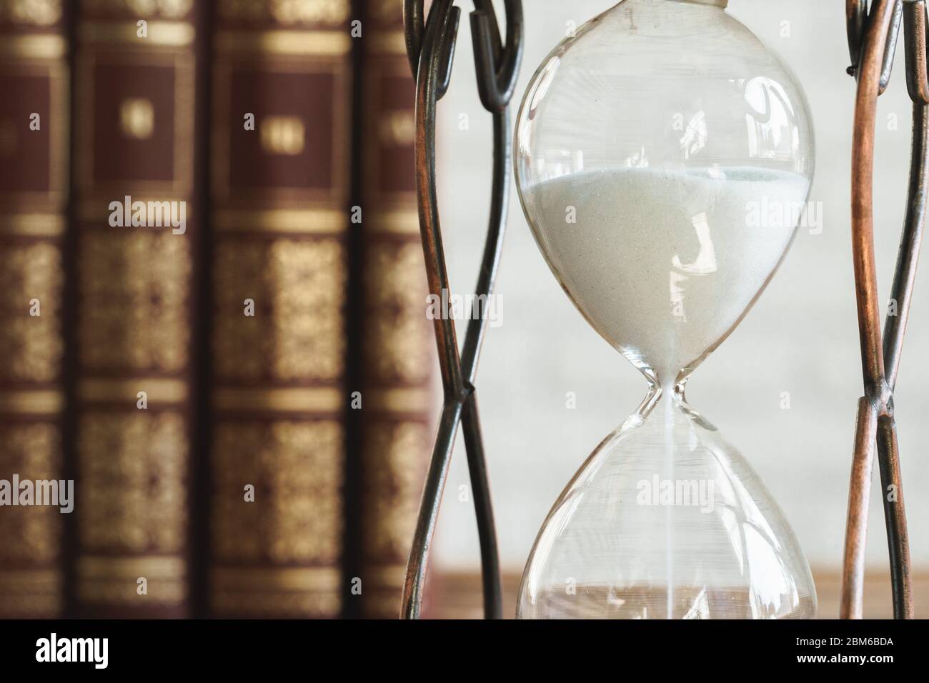 Vintage hourglass against a stack of old books Stock Photo - Alamy