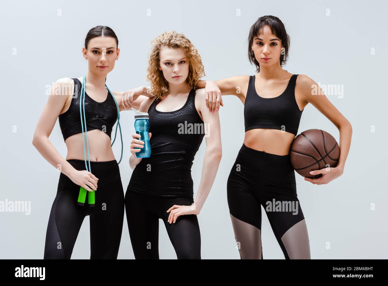 attractive and multicultural girls standing with sport equipment ...