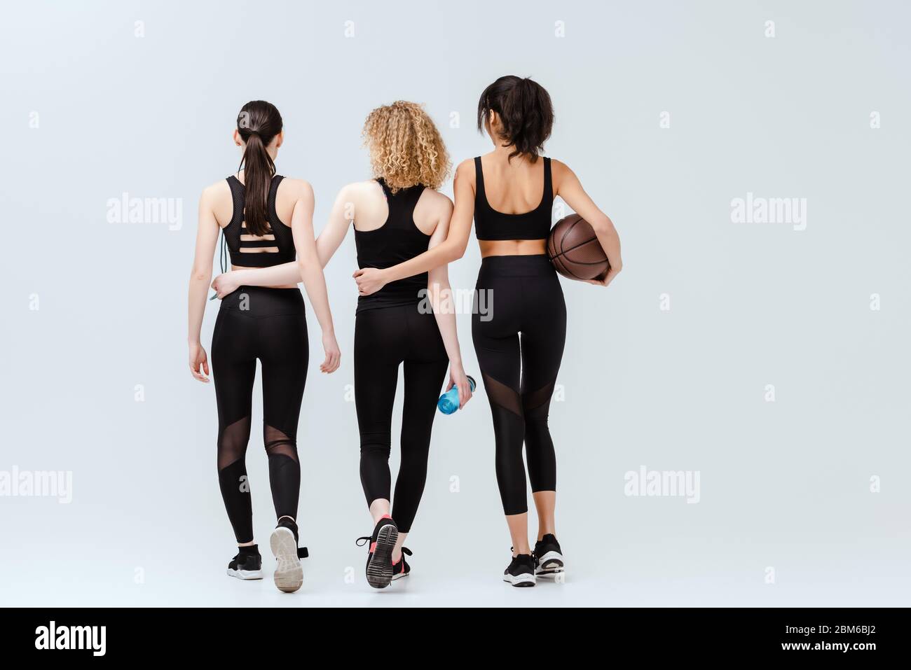 back view of multicultural girls walking with sport equipment on white ...