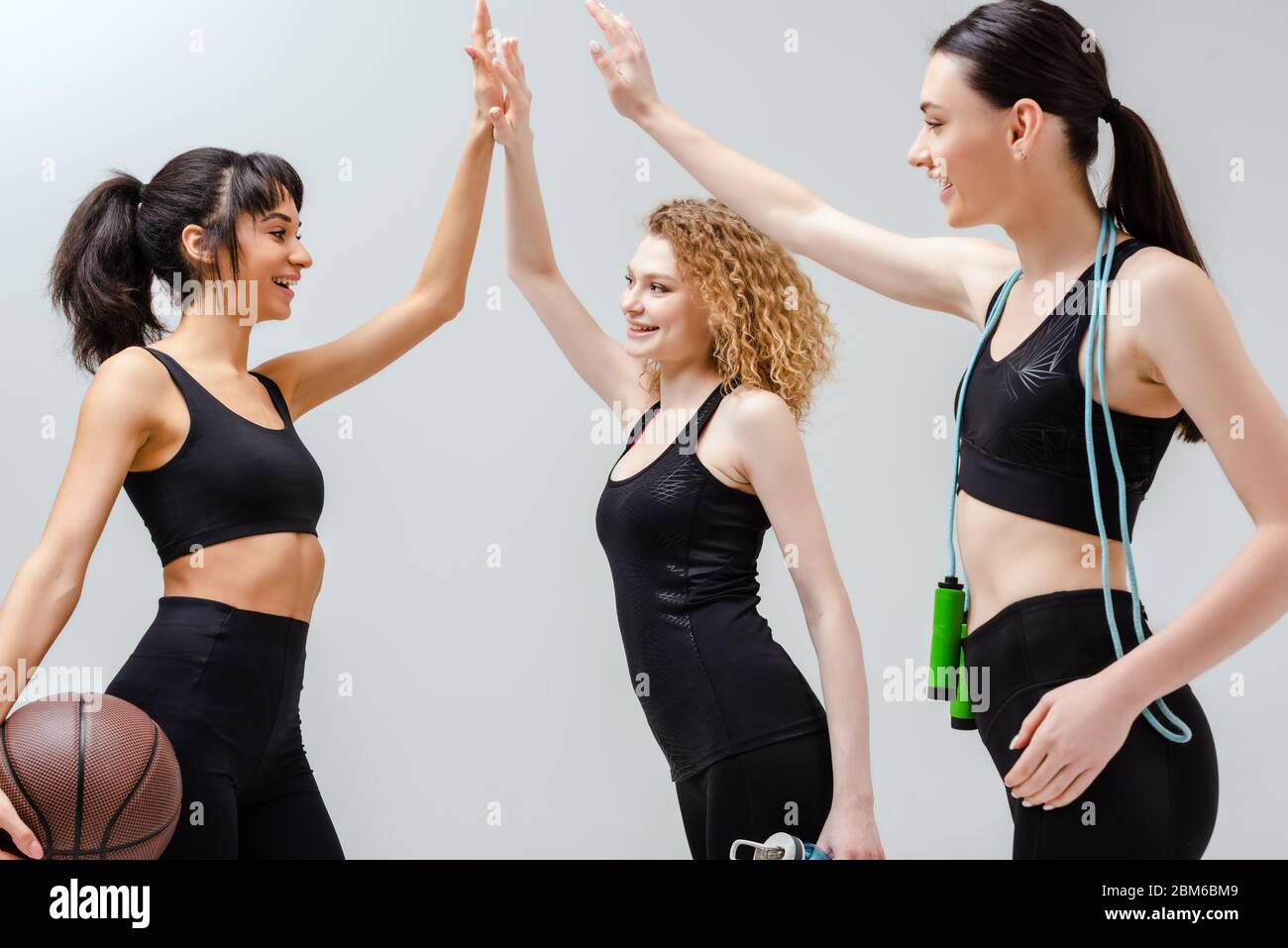 happy multicultural girls in sportswear giving high five on white Stock ...