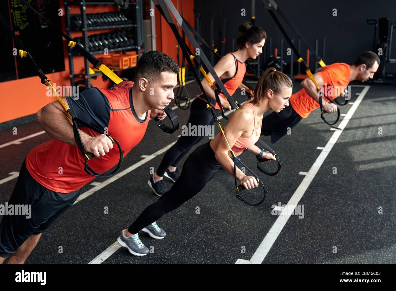 Sporty Lifestyle. Young people doing clock press TRX exercise at gym ...