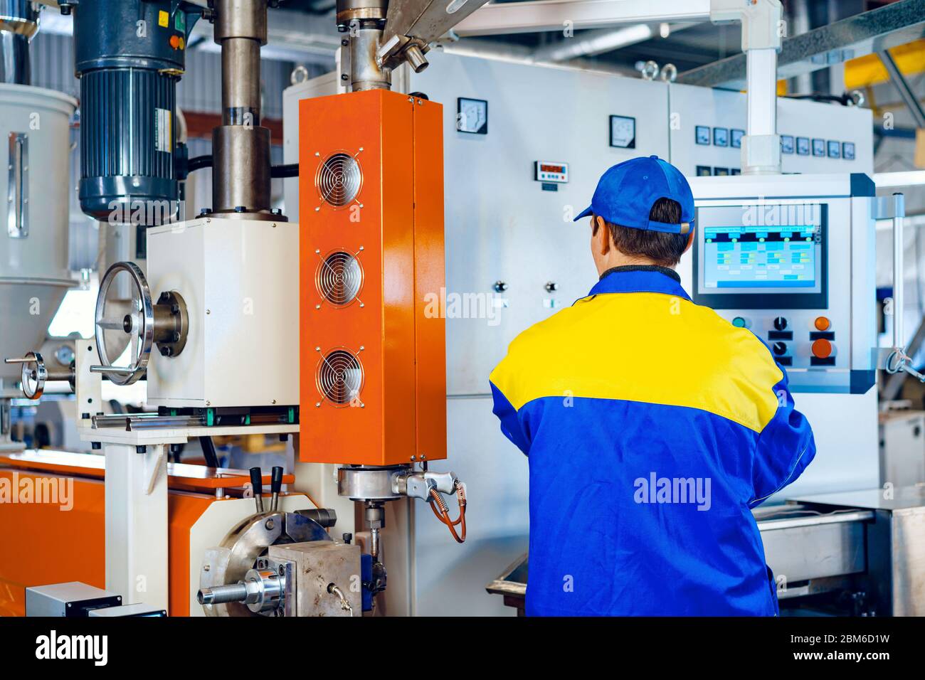 Man worker in manufacturing plant at cable factory machine control ...
