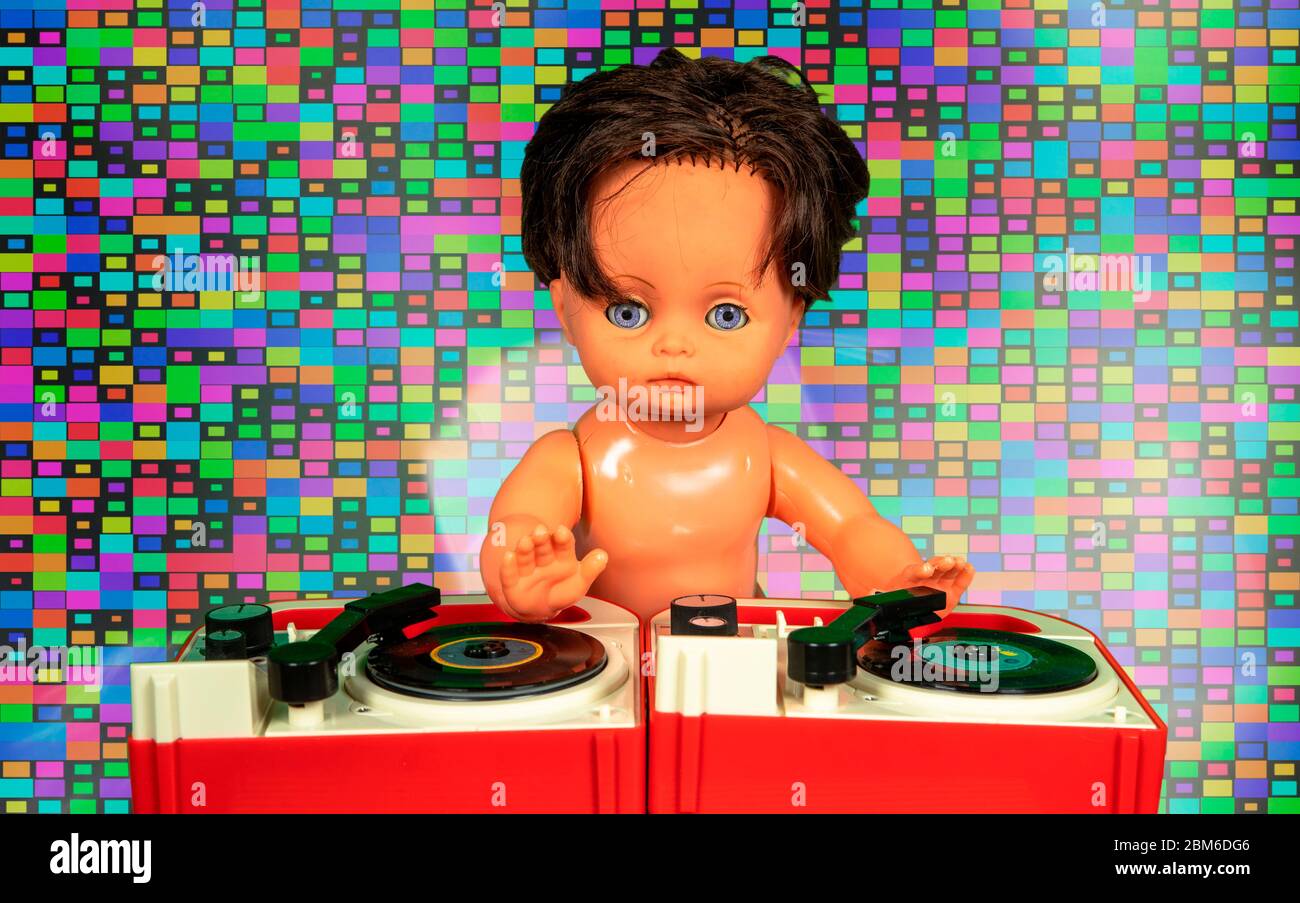 Toy plastic doll DJ playing vinyl on the decks with disco squares ...