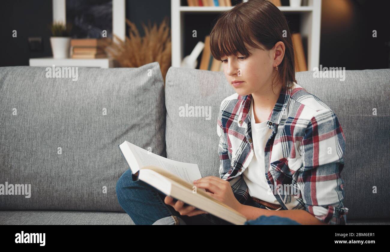 Teenager reading book on sofa Stock Photo - Alamy
