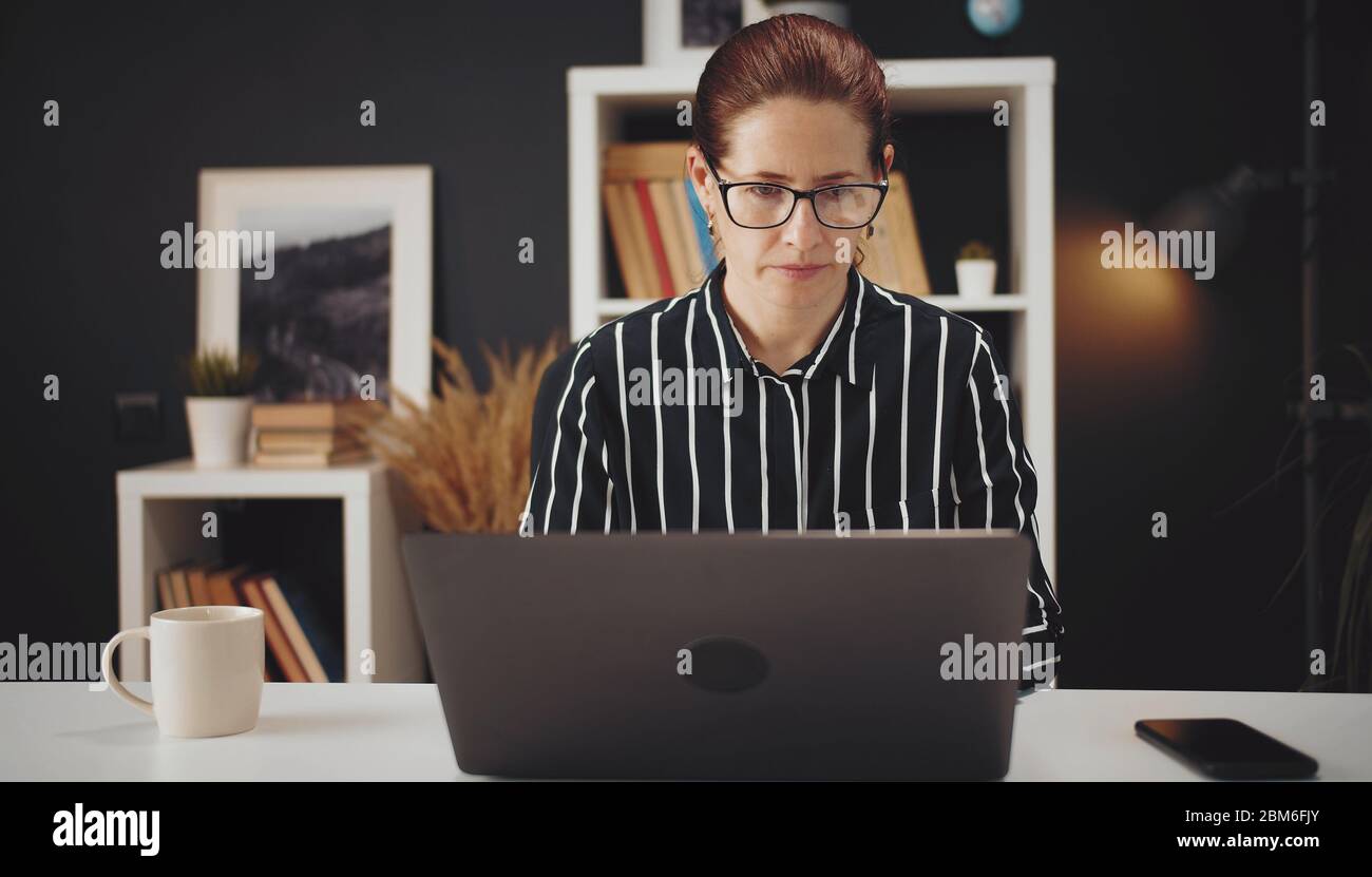 Serious woman working from home Stock Photo - Alamy