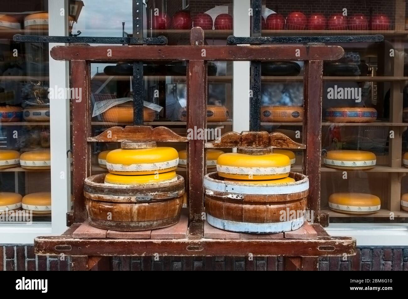 Different types of cheese displayed in front of and in the display case ...