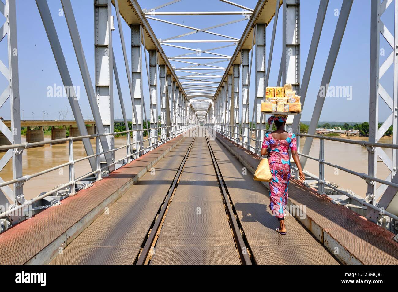 Woman with a load on her head crossing river Niger using the railway ...