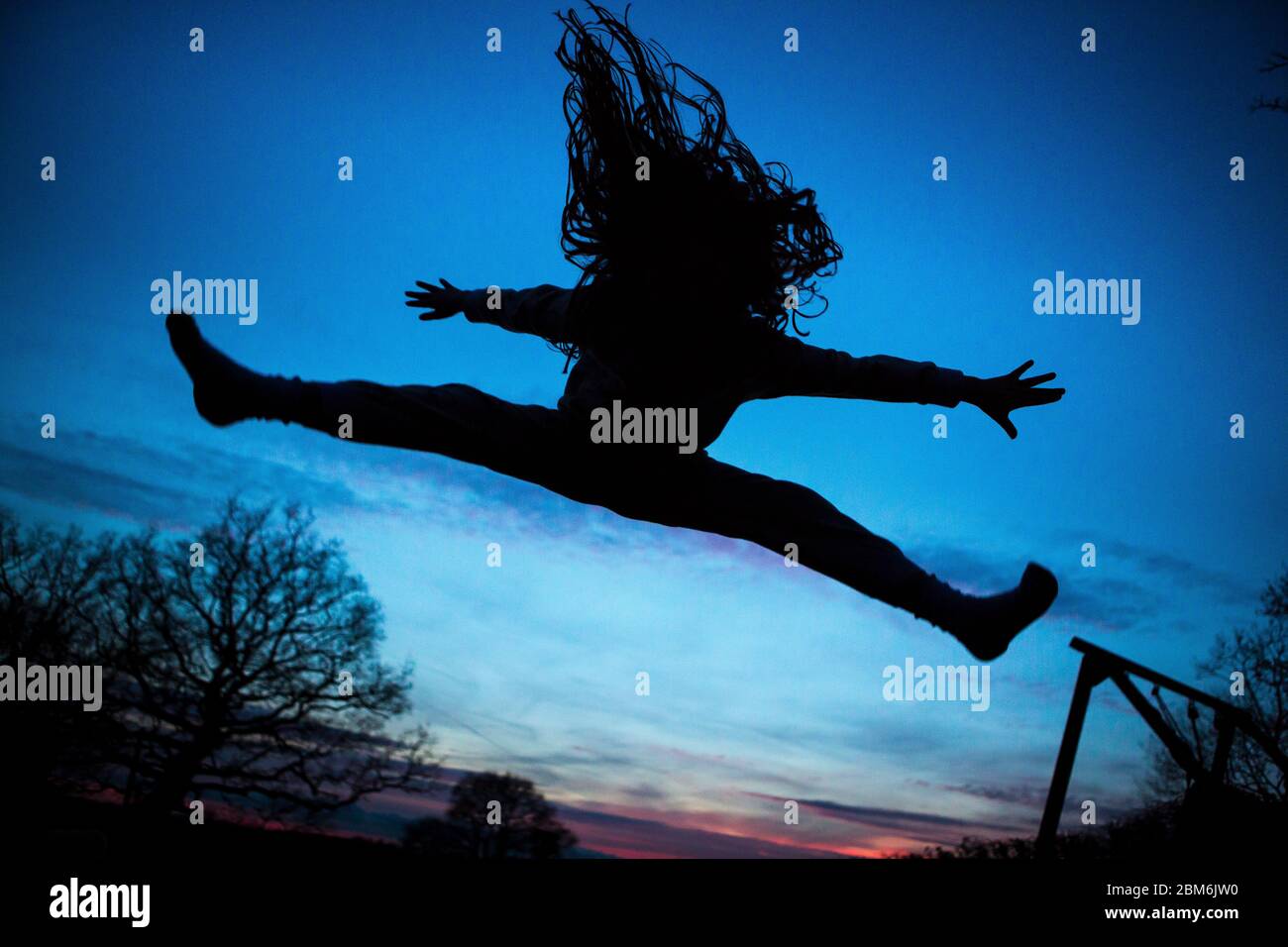 Young girl doing the splits in the air whilst jumping high on a ...