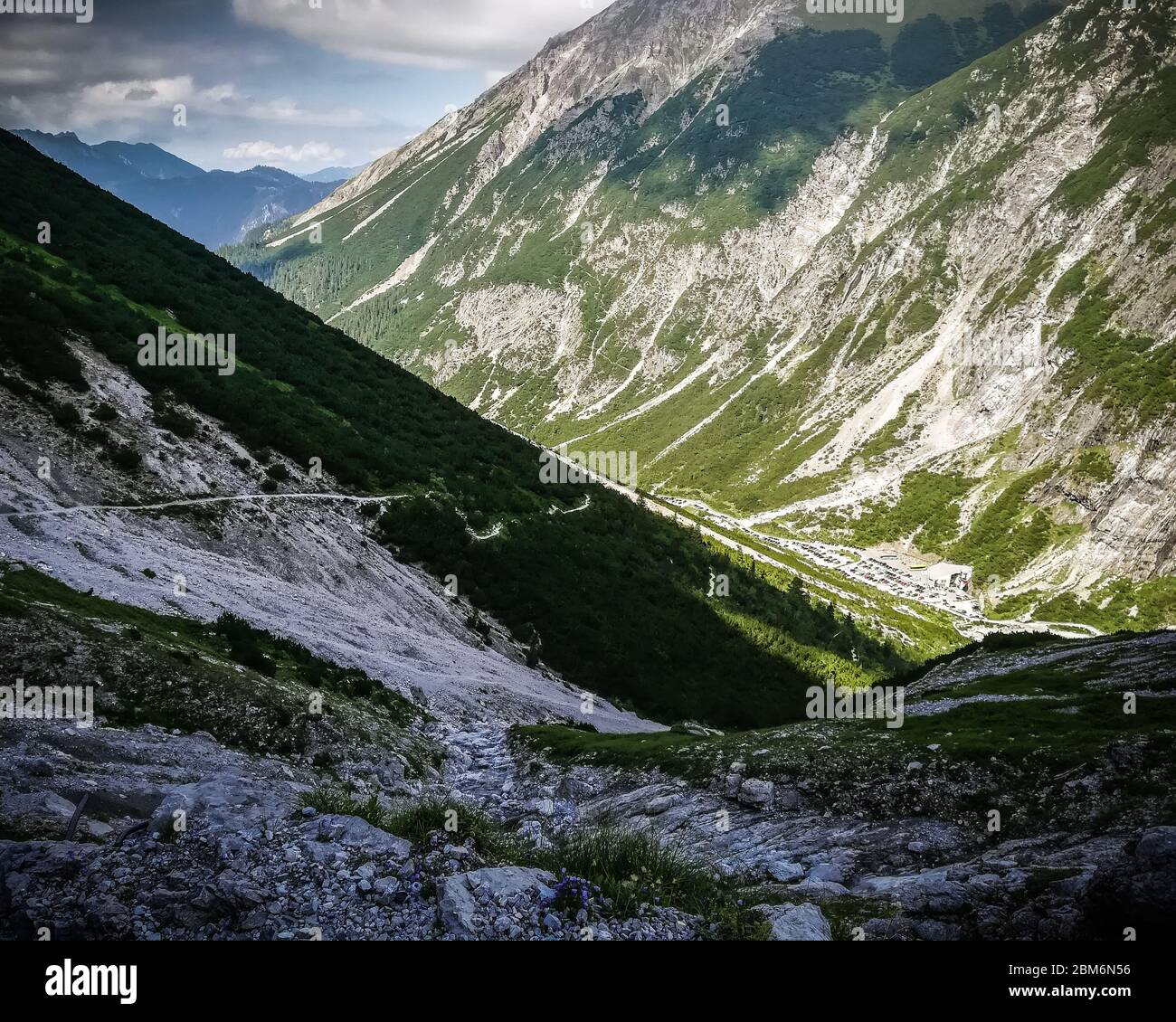 Narrow and difficult rocky trekking trail across mountain to a lake ...