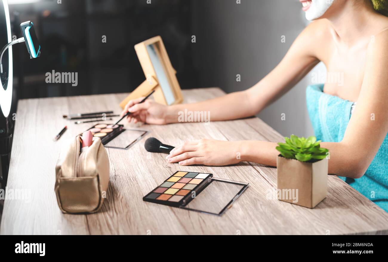 Young female vlogger applying make up while recording video for web ...