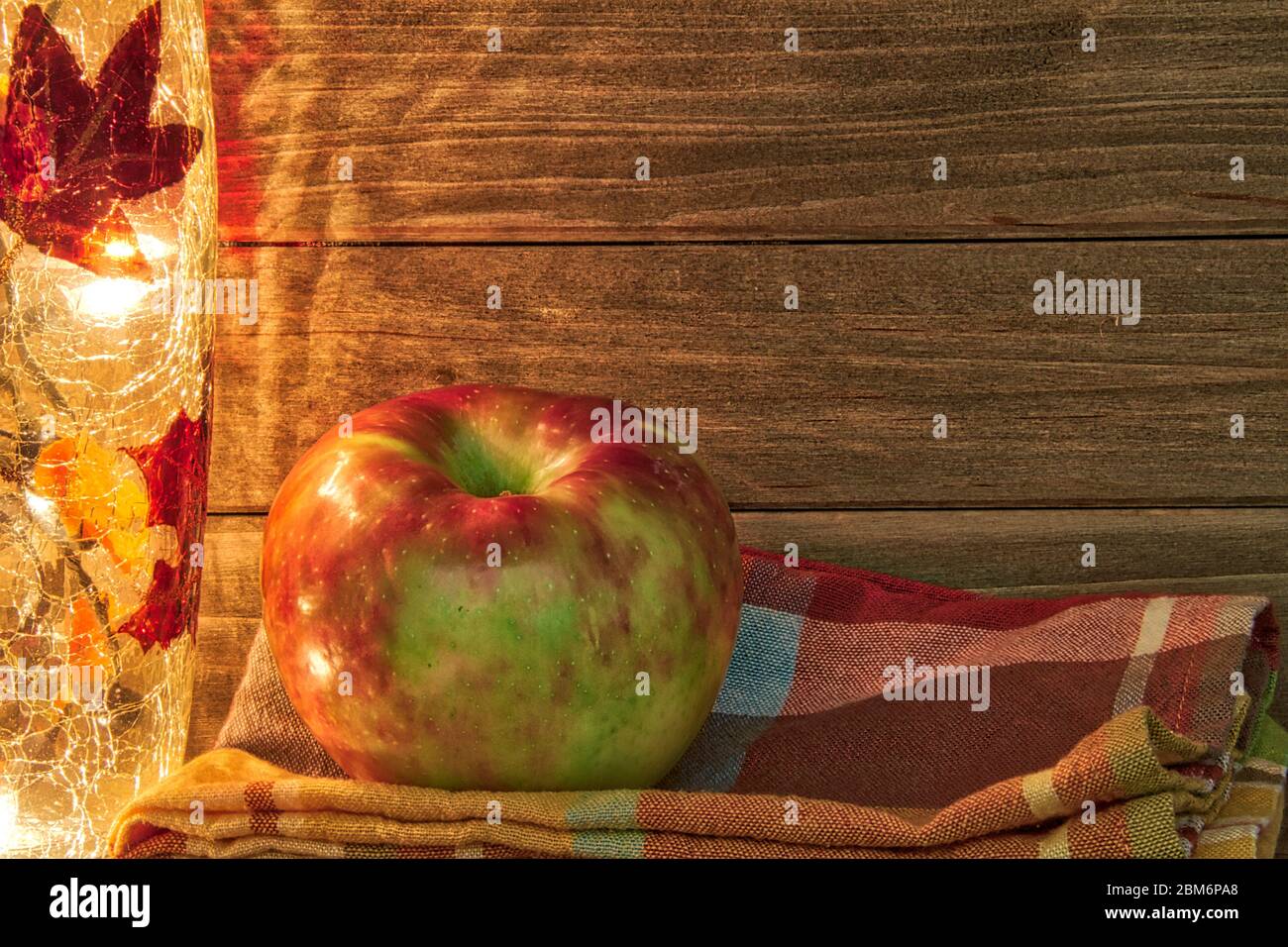 Apple in a fall theme with light and napkin and a wood background ...