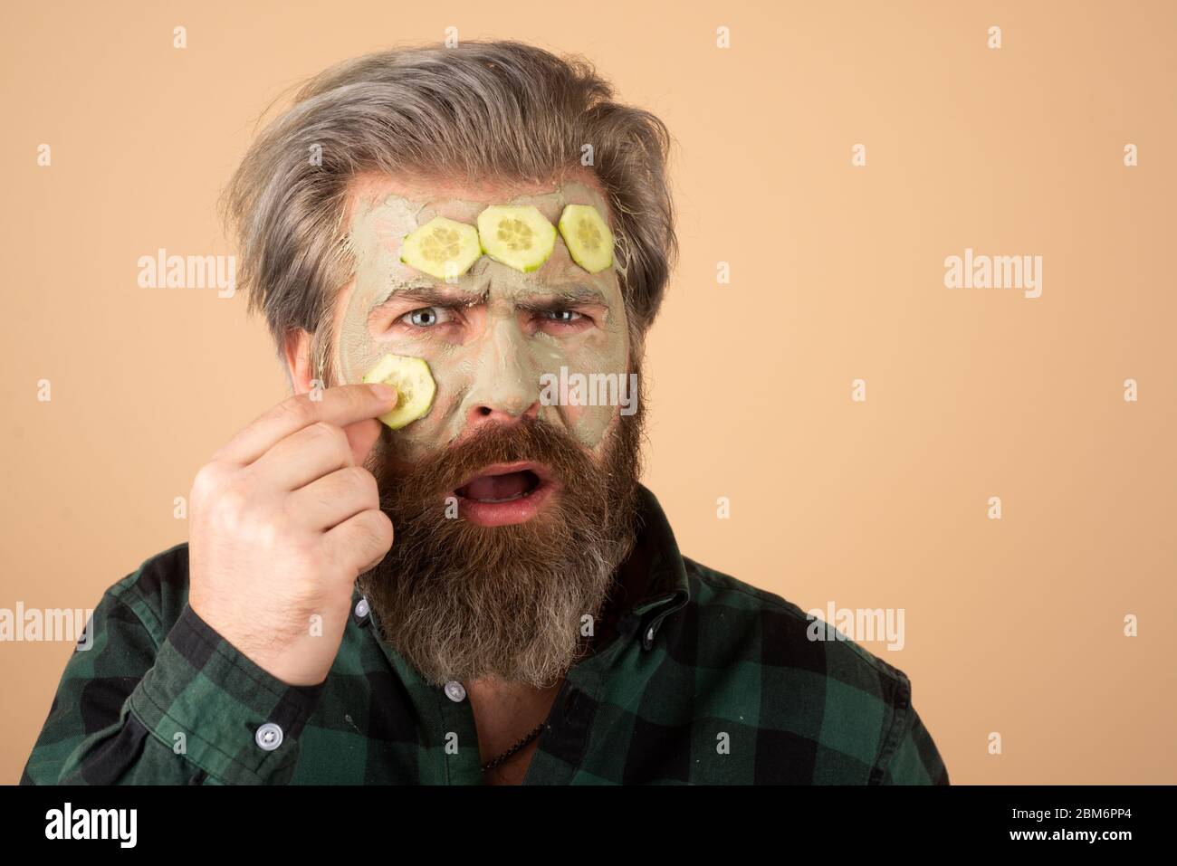 Funny man with facial mask. Man getting facial care with cucumber ...