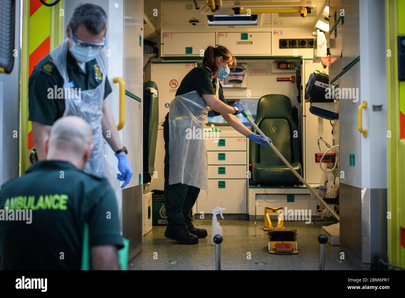 An ambulance crew member wearing protective clothing disinfects the ...