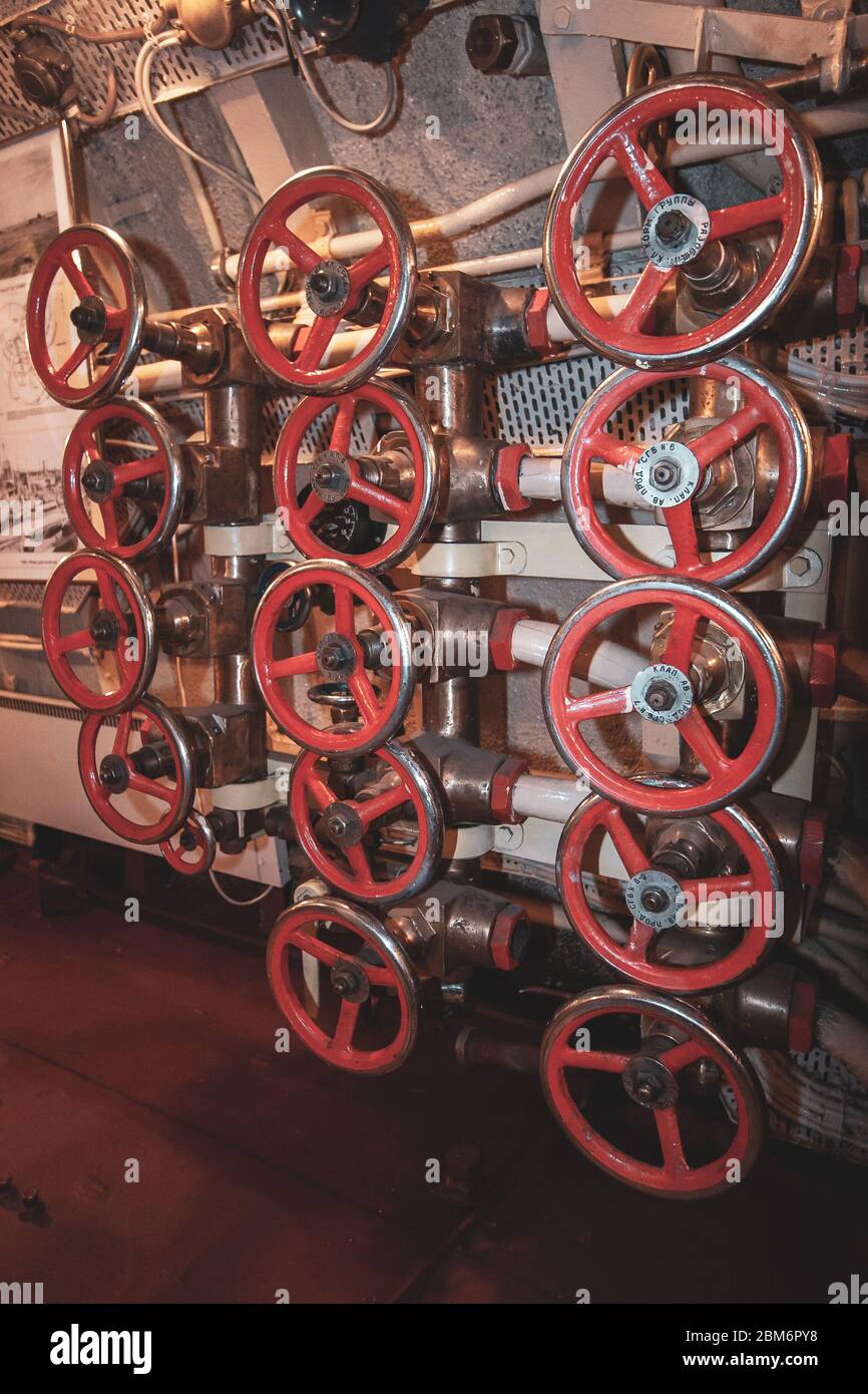 Many round cranes for closing valves on a ship. Red hilt. Horizontal ...