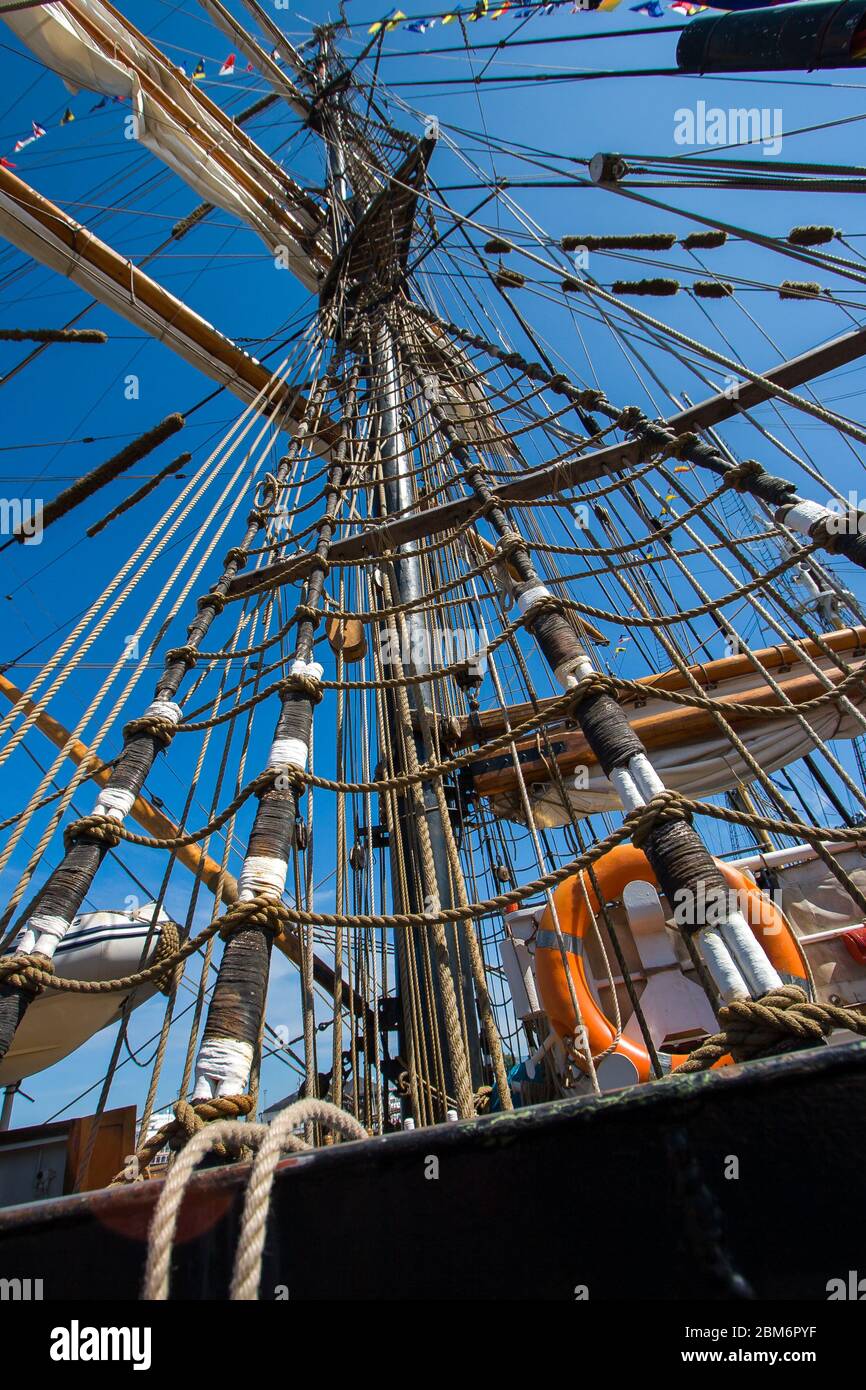 High mast with sails and rope ladders against the blue sky. Lifebuoy ...