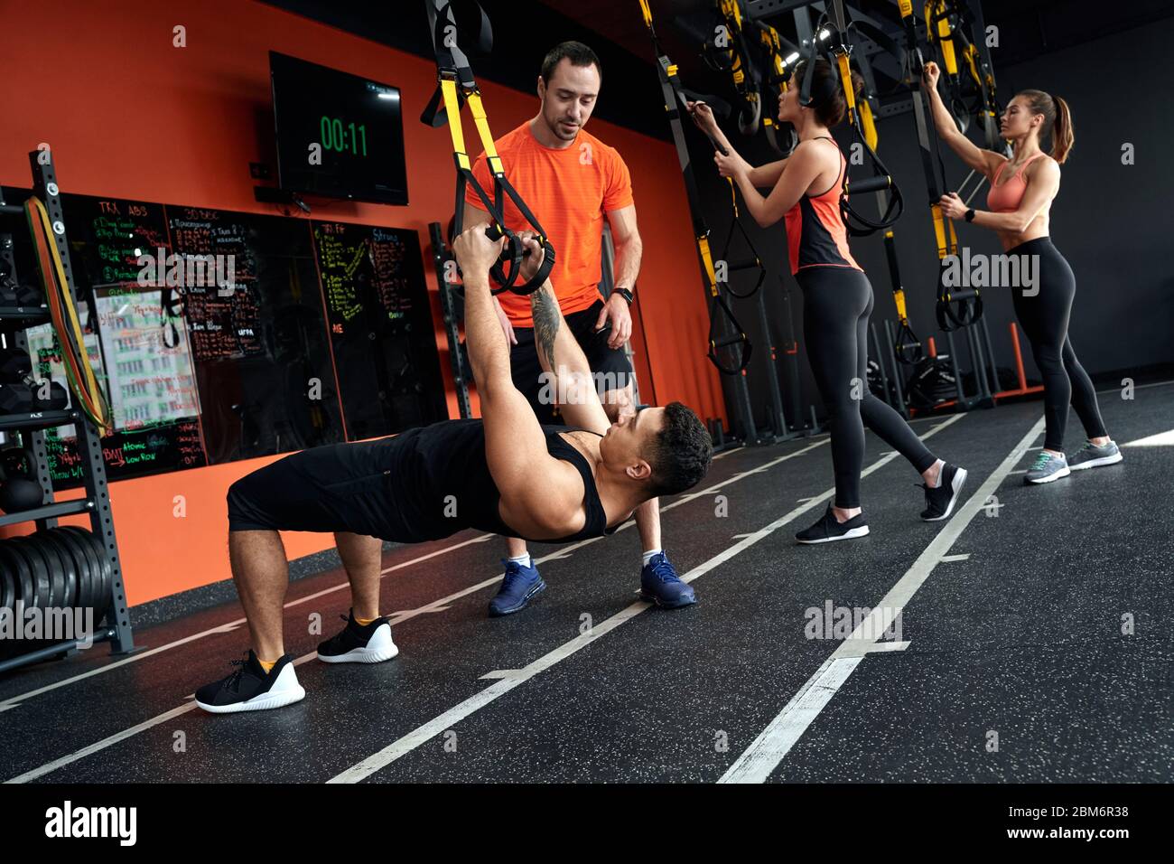 Group of young adult sporty people training with coach and trx Stock ...