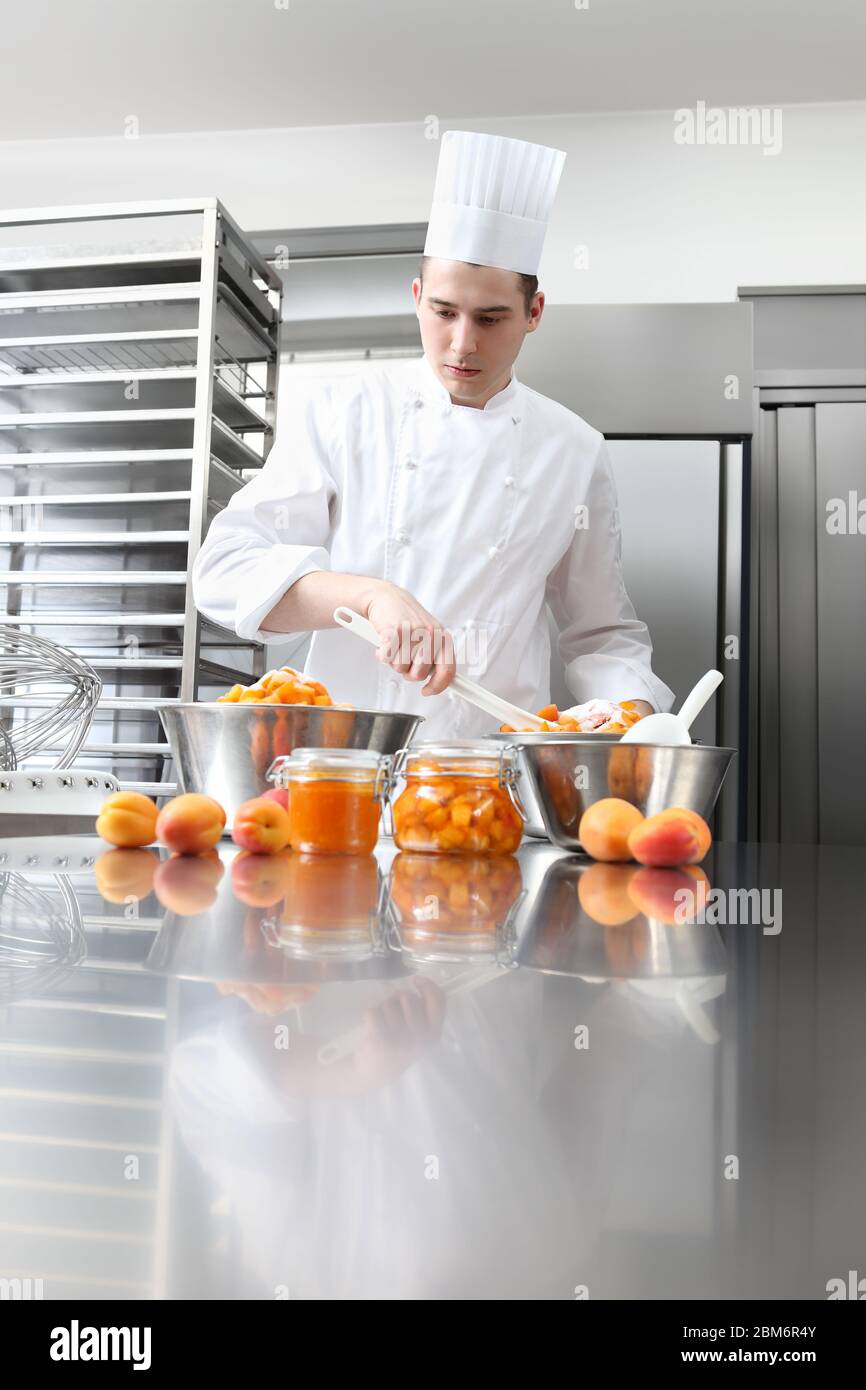 pastry chef at work in professional kitchen, makes apricot jam for the ...