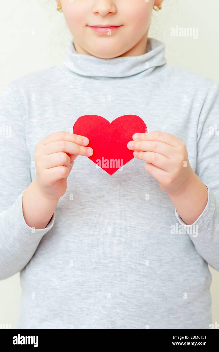 Red heart in hands of little girl on white background. Child is holding ...