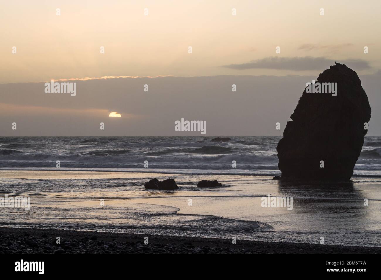 Sunset scene in Gold Beach Oregon with colorful clouds and waves adding ...