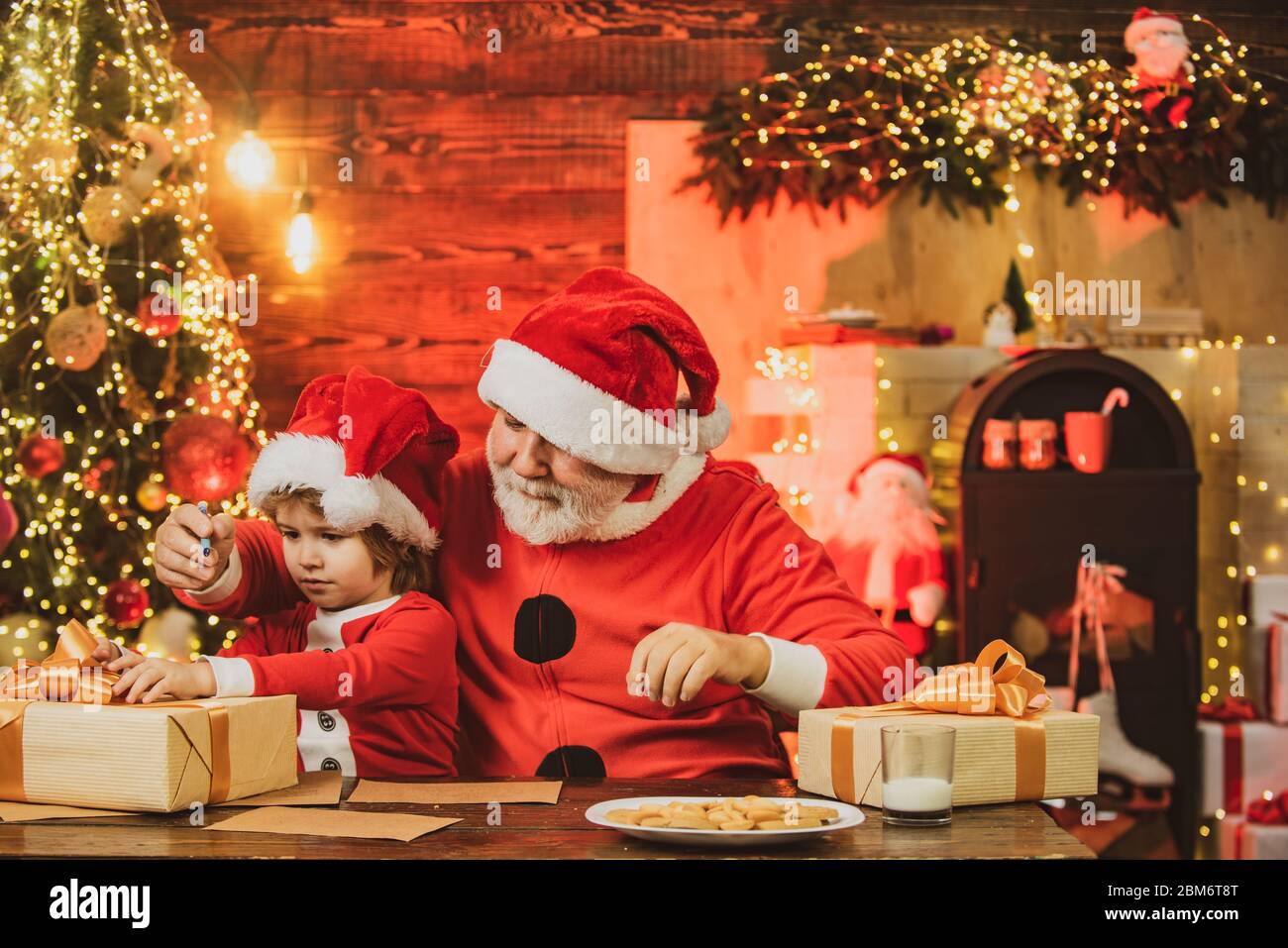 Portrait of cheerful dreamy granny Santa and grandchild writing letter ...