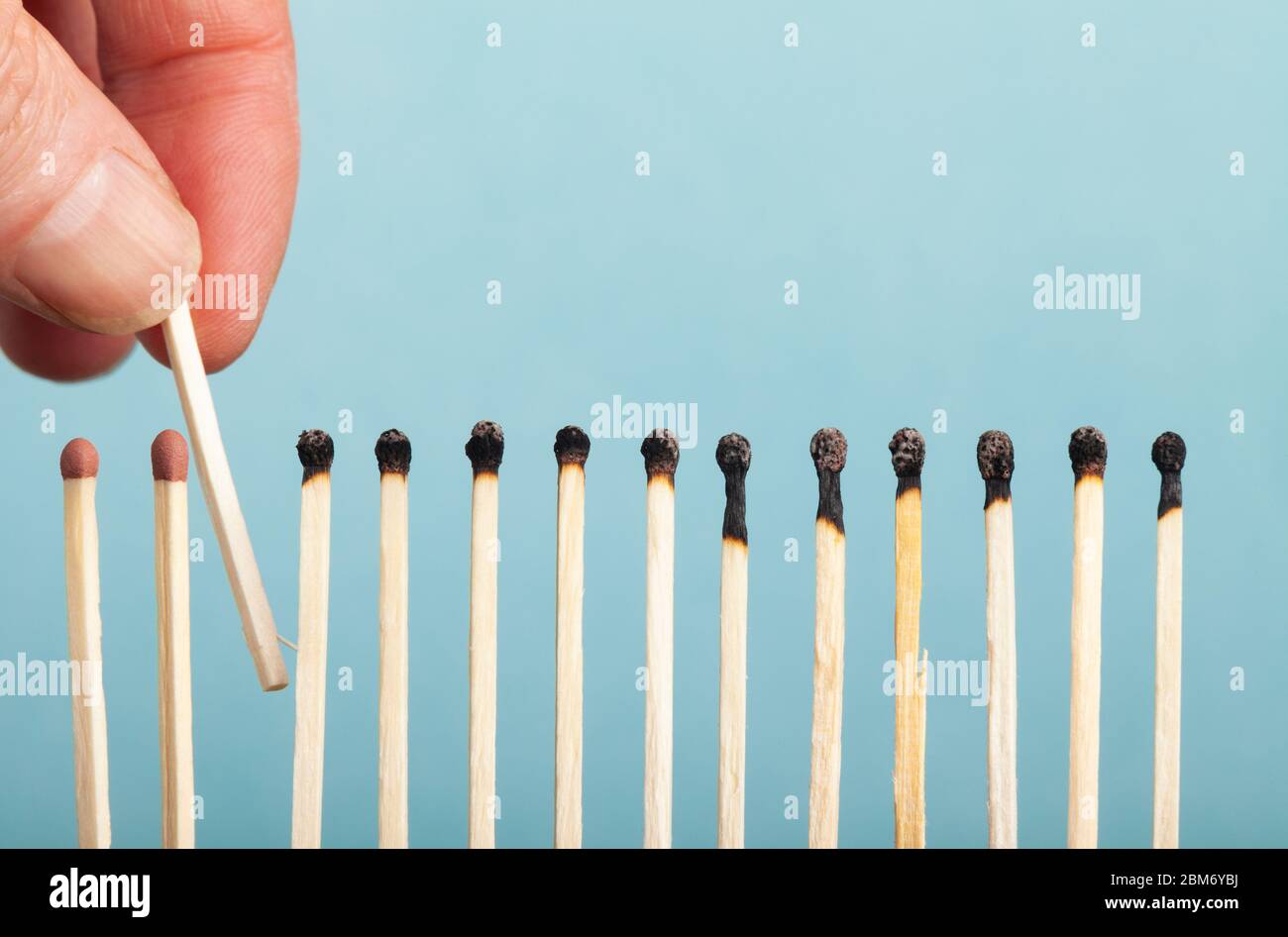 A row of matchsticks with a hand picking one out of the line Stock ...